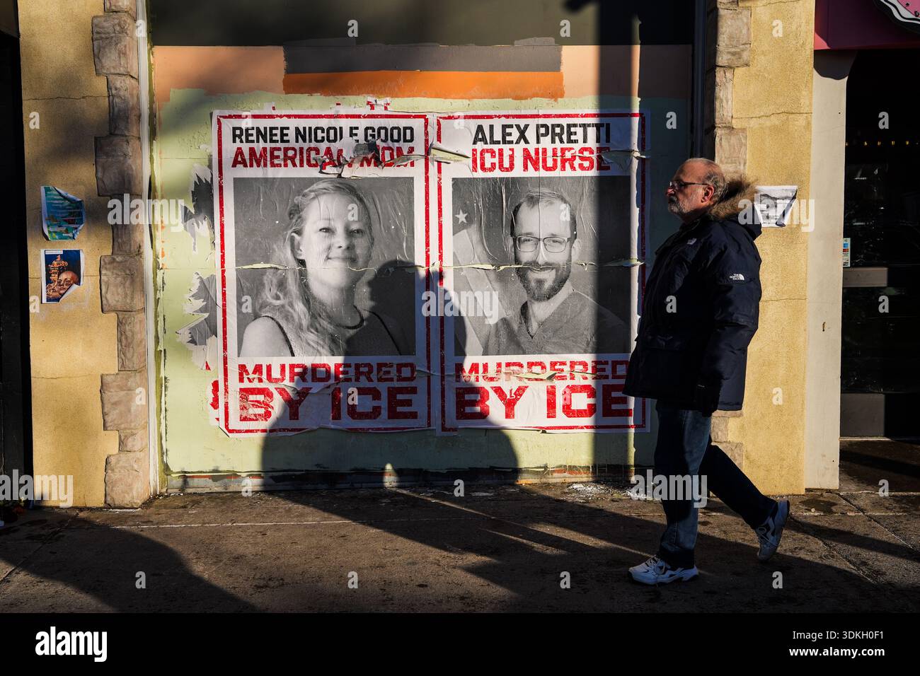 A man walks by posters of Renee Nicole Good and Alex Pretti, who were ...
