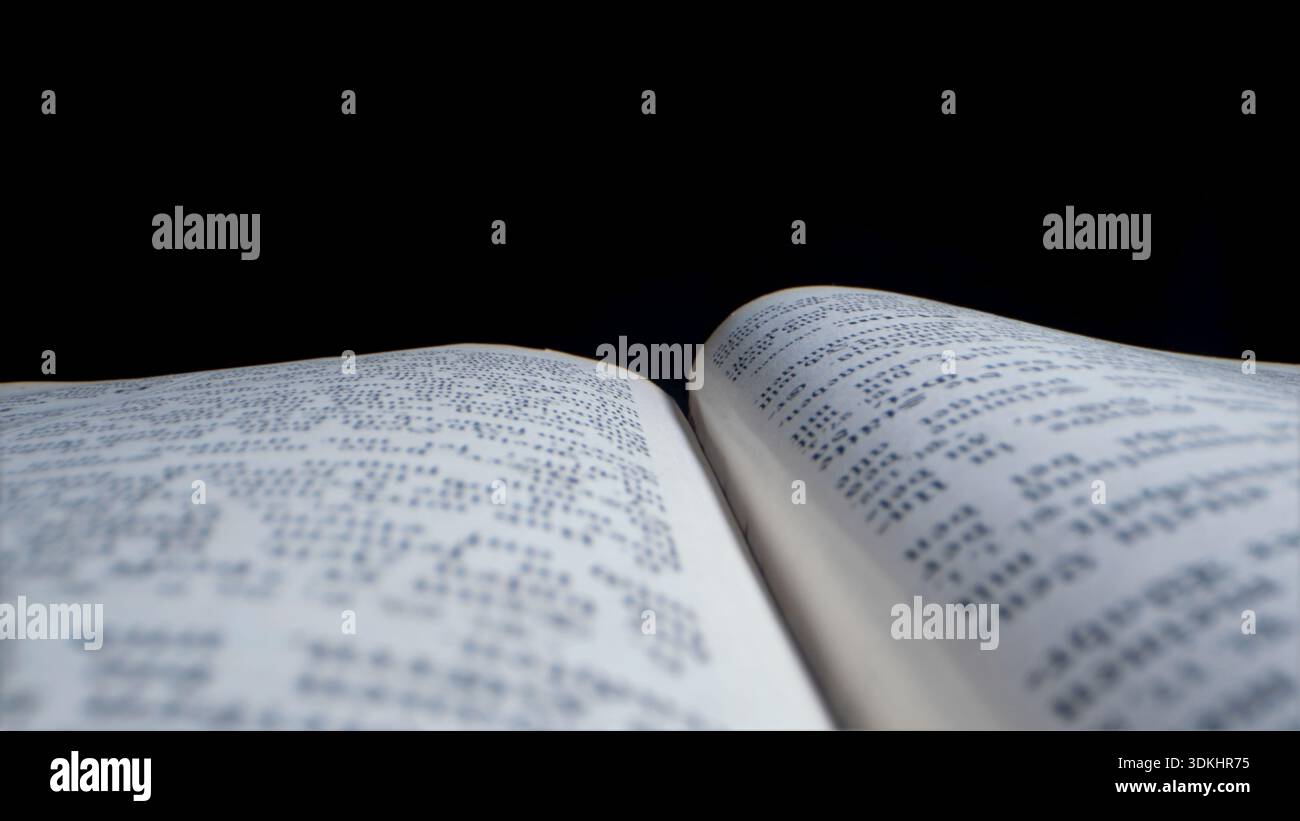 Open book with pages displaying text, placed on a dark surface, close ...