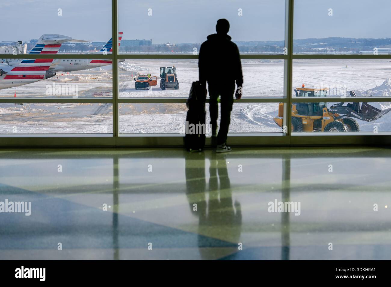 A passenger watches as snow and ice is cleared at Ronald Reagan ...