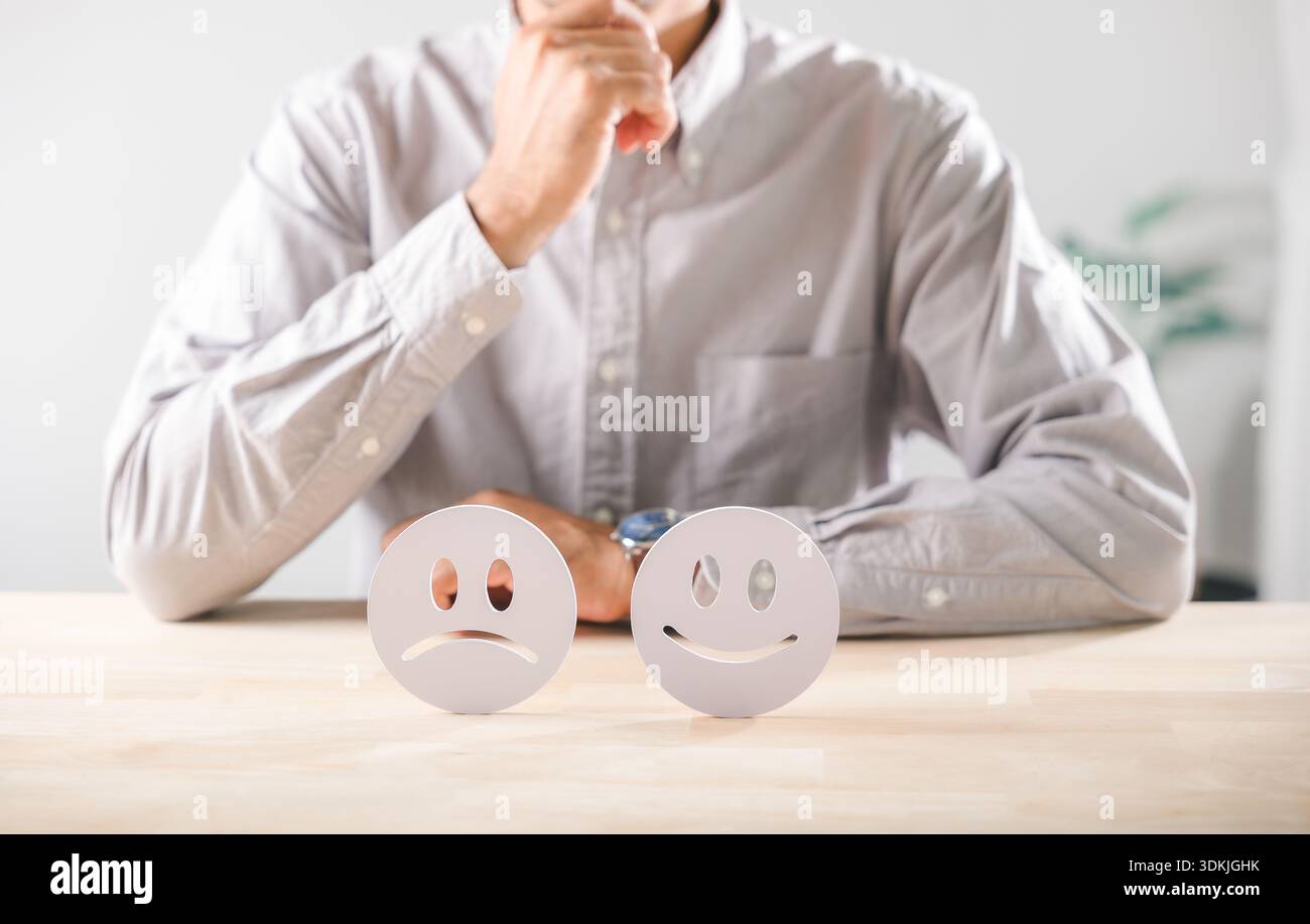 Man considering emotional contrast, happy sad faces on table ...