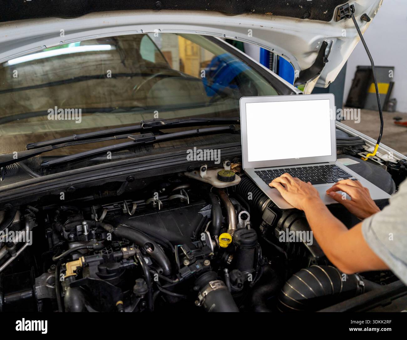 Auto mechanic using laptop to inspect engine under car hood Stock Photo ...