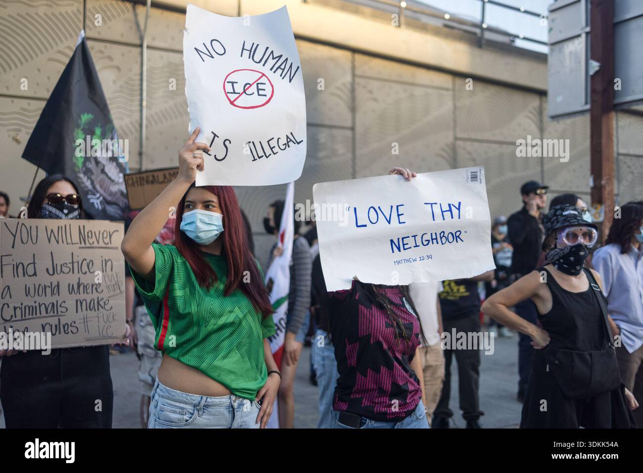 Protesters hold placards saying “No Human Is Illegal” and “Love Thy ...