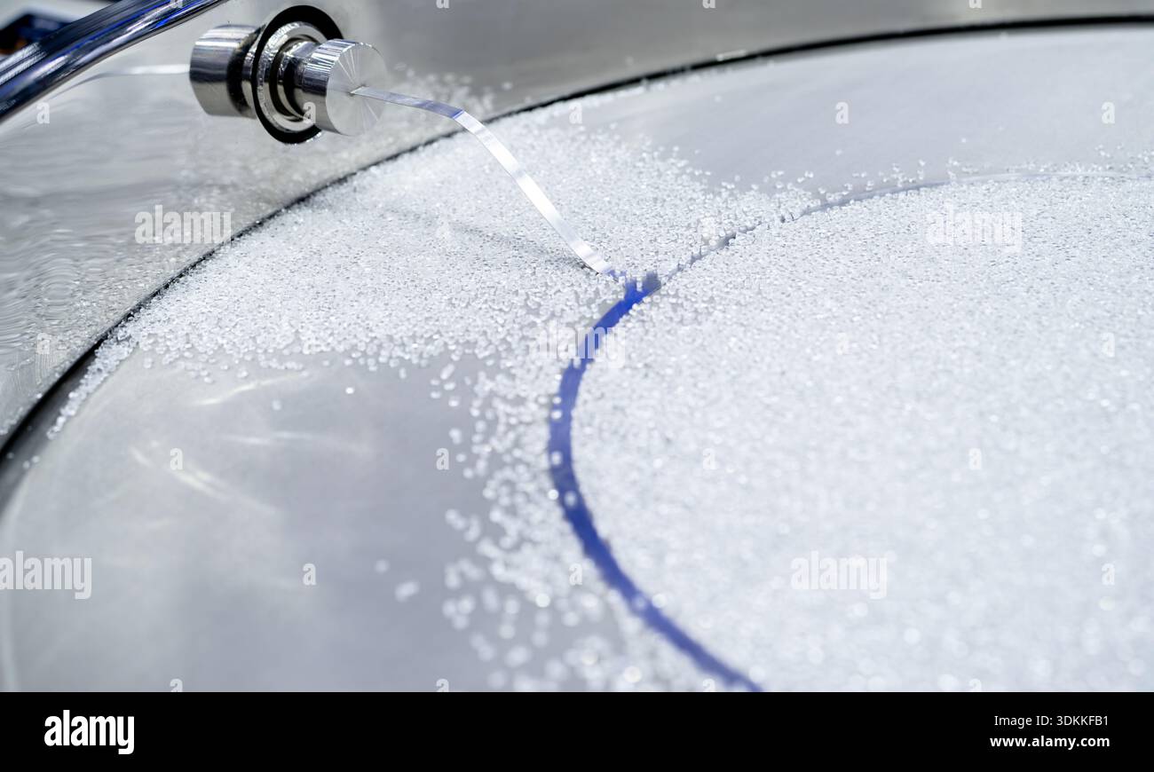 Close up of plastic resin pellets flowing inside stainless steel ...
