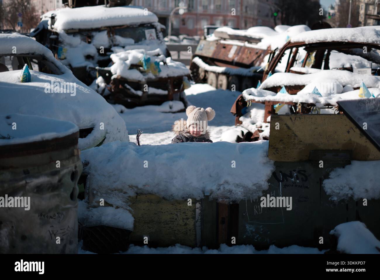 Children play with snow in the remains of destroyed combat vehicles ...