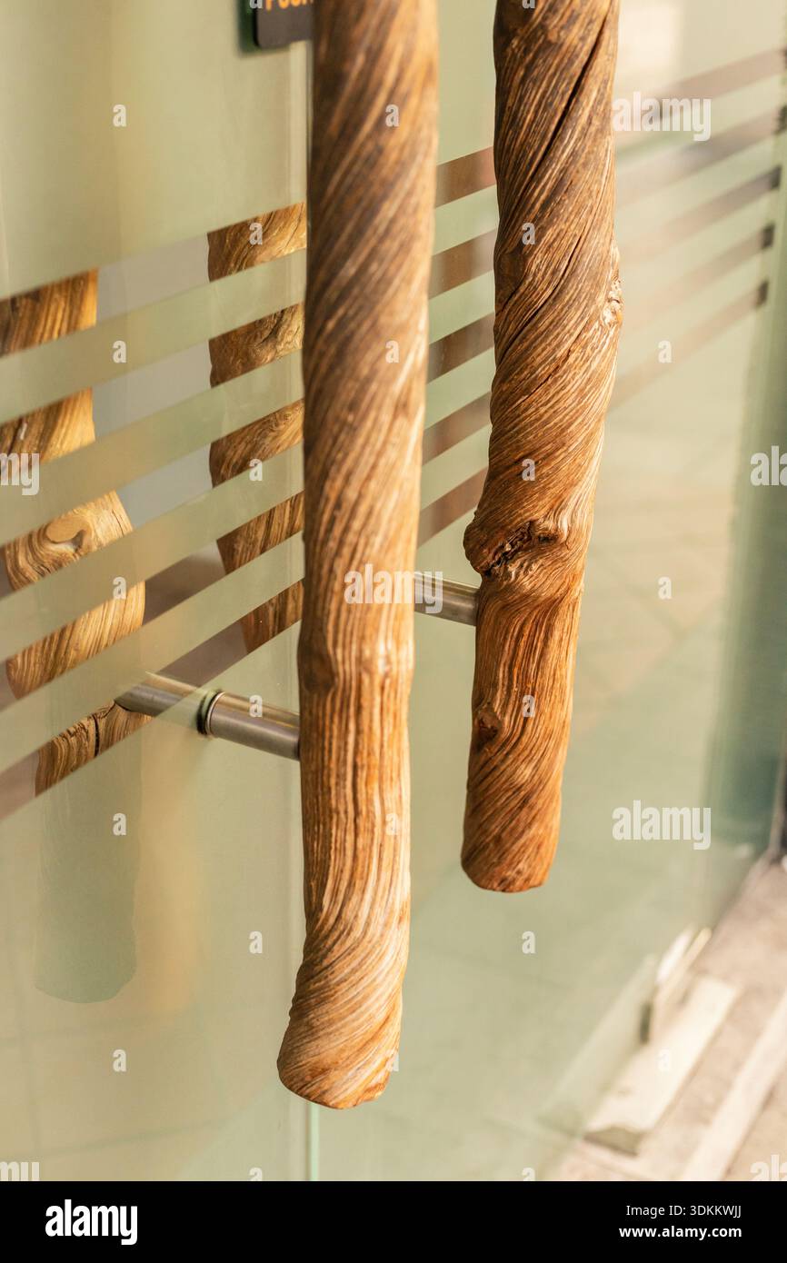 Two wooden door handles are attached to a glass door in a contemporary ...