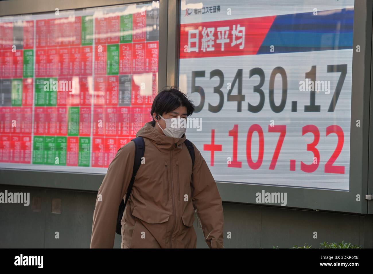 A person walks in front of an electronic stock board showing Japan's ...
