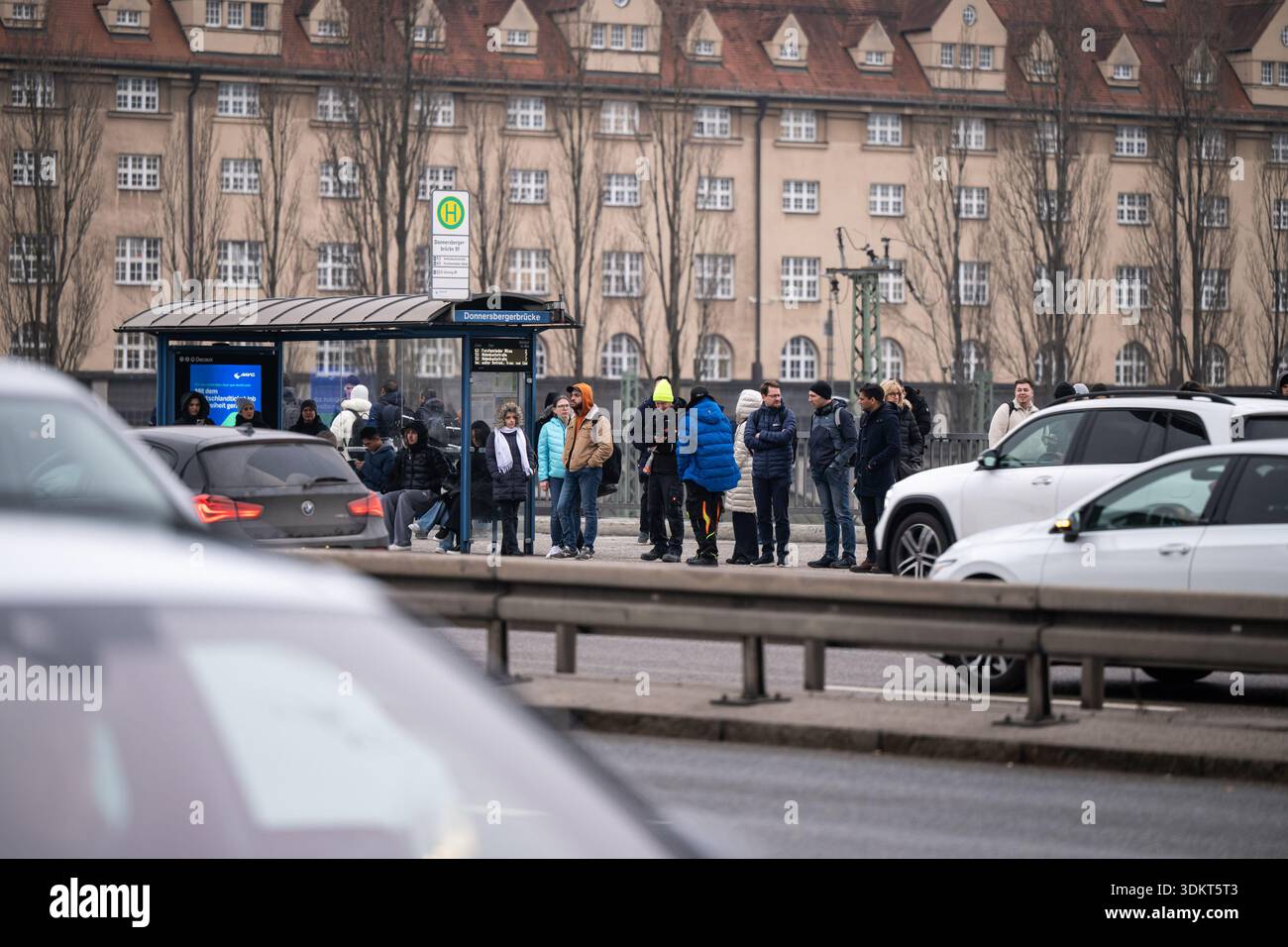 02 February 2026, Munich: Passengers wait for a bus during a nationwide ...