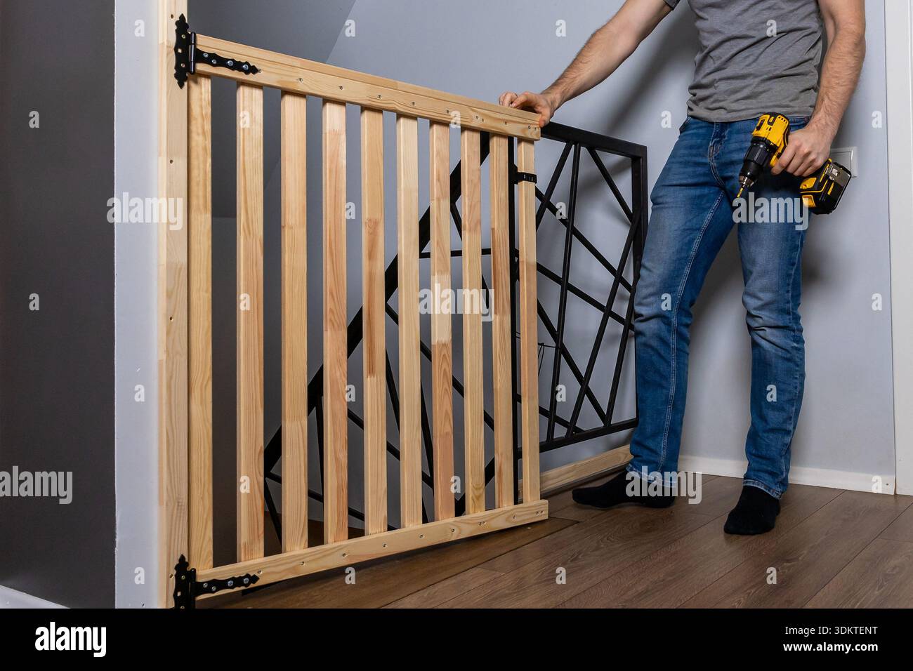 Individual uses a yellow and black power drill to install a wooden ...
