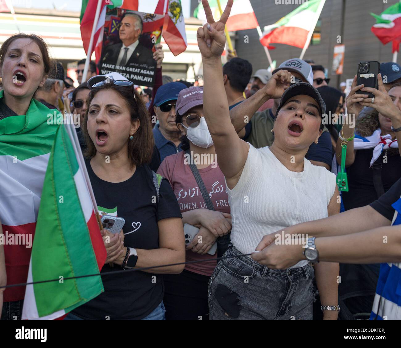 Protesters chant and raise their arms while waving Iranian flags during ...
