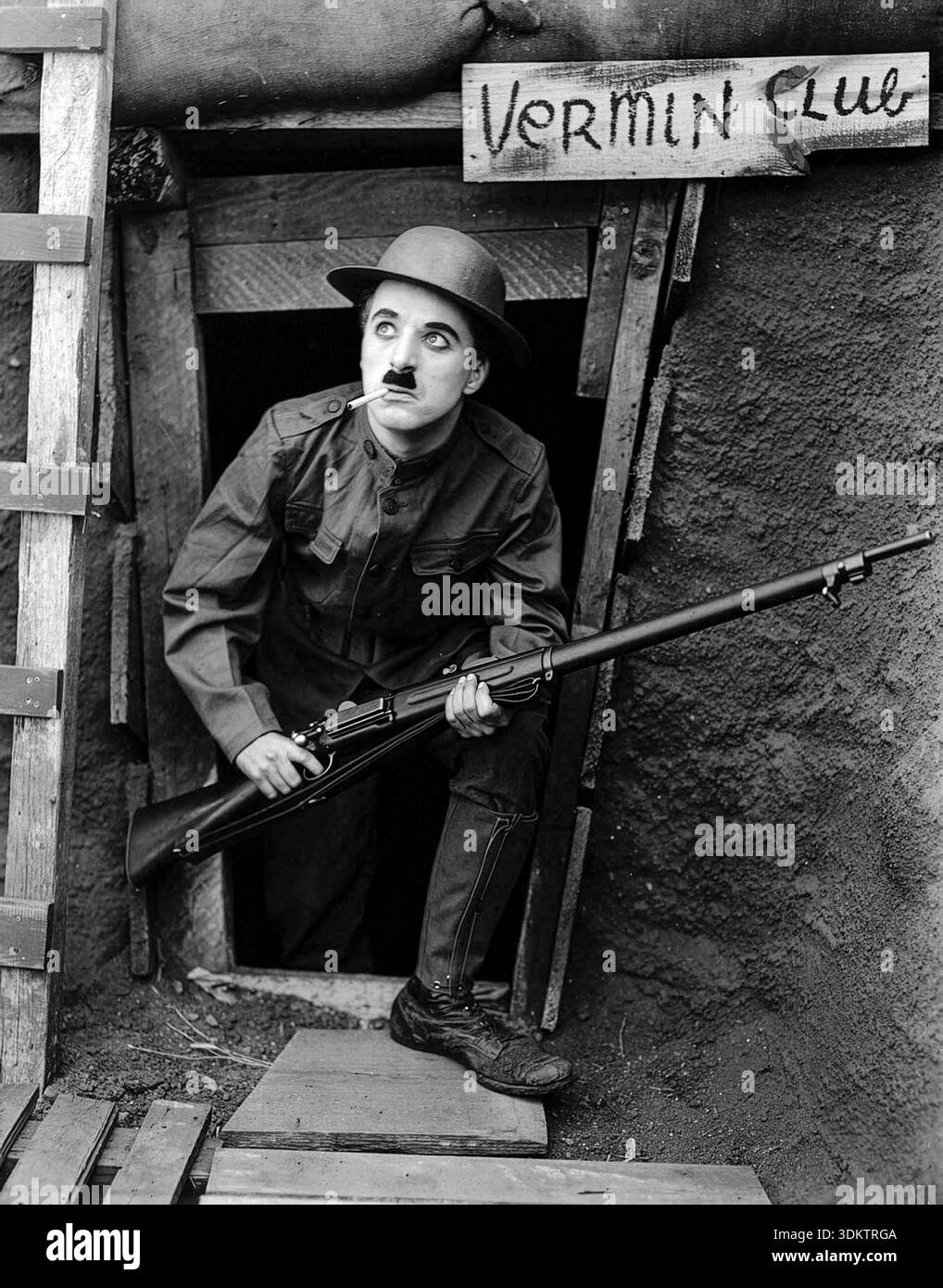 Charlie Chaplin as 'The Tramp' emerges cautiously from a dugout labeled ...