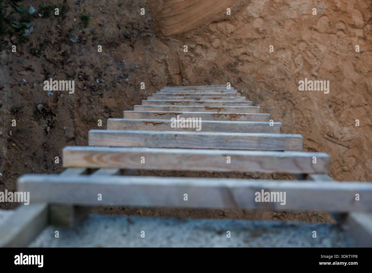 Top down view of a wooden ladder leading into a deep excavation site ...