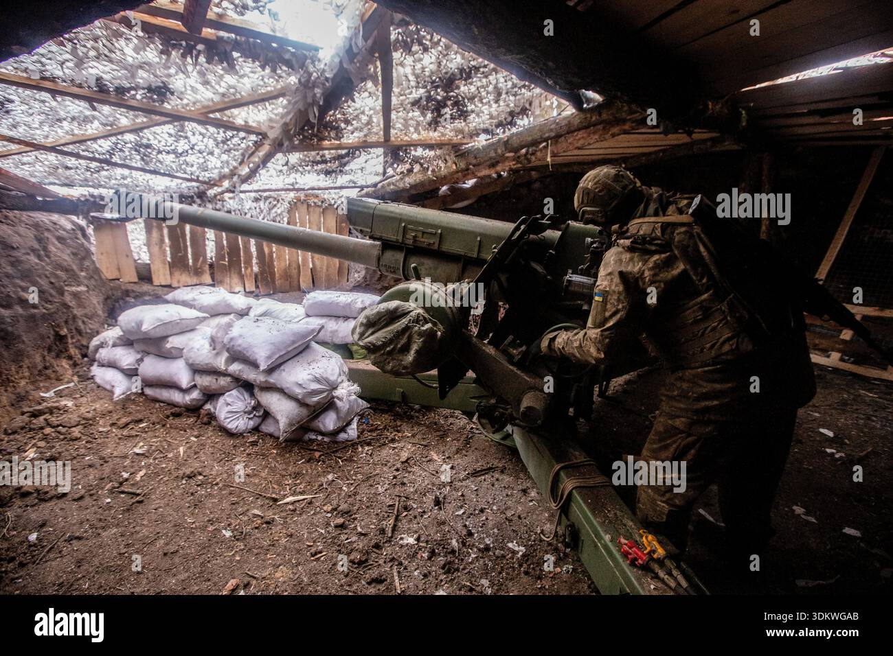 Ukrainian gunner working on a D30 artillery cannon. In the cold of ...