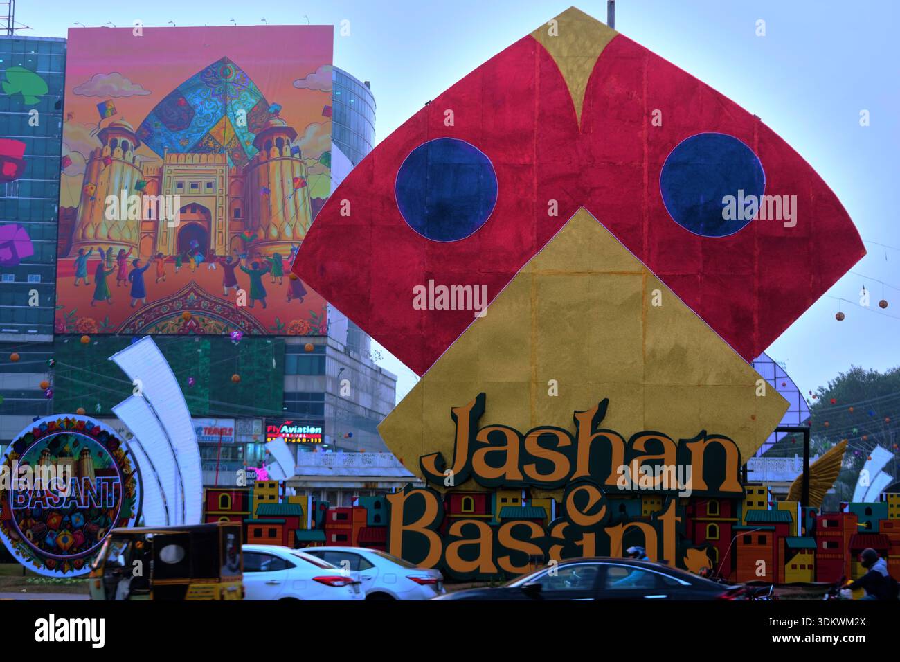 Vehicles drive past a giant kite model placed by local administration ...