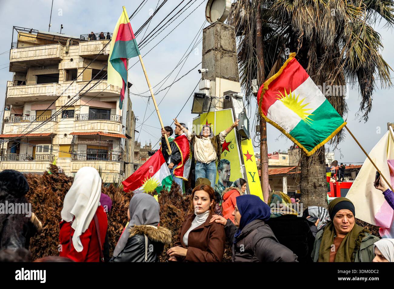 Kurdish demonstraters stand on a structure and wave Kurdistan flags ...