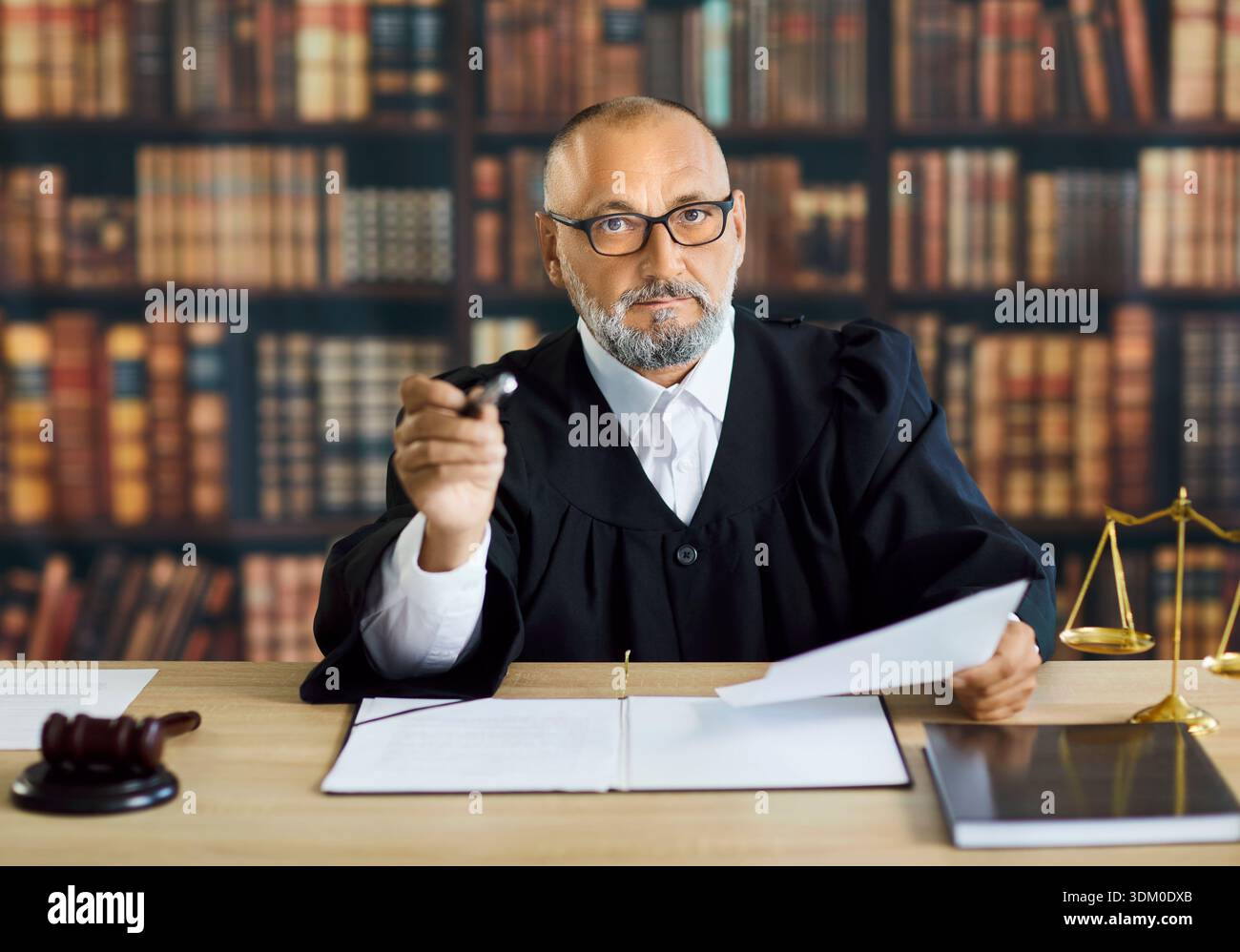 Experienced judge pointing with pen while reading papers at desk, law ...