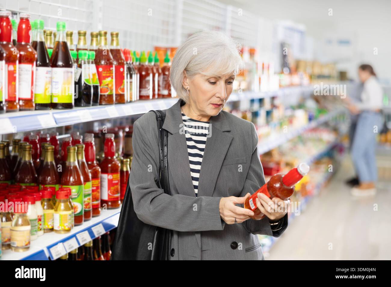 Senior woman customer is thinking about buying spicy and unusual red ...