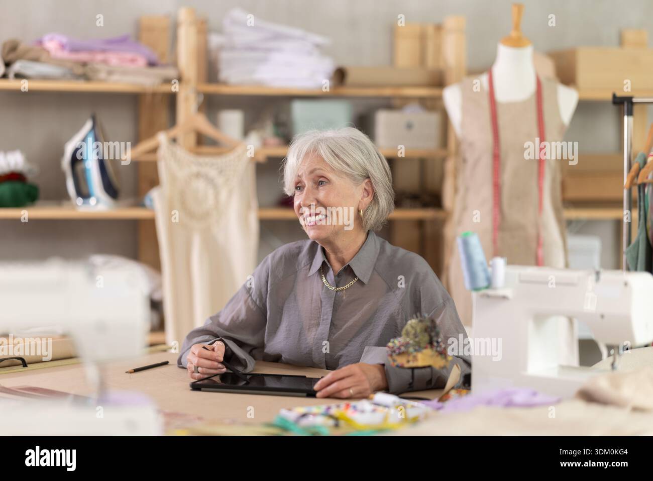 Mature dressmaker drawing sketch on tablet Stock Photo - Alamy
