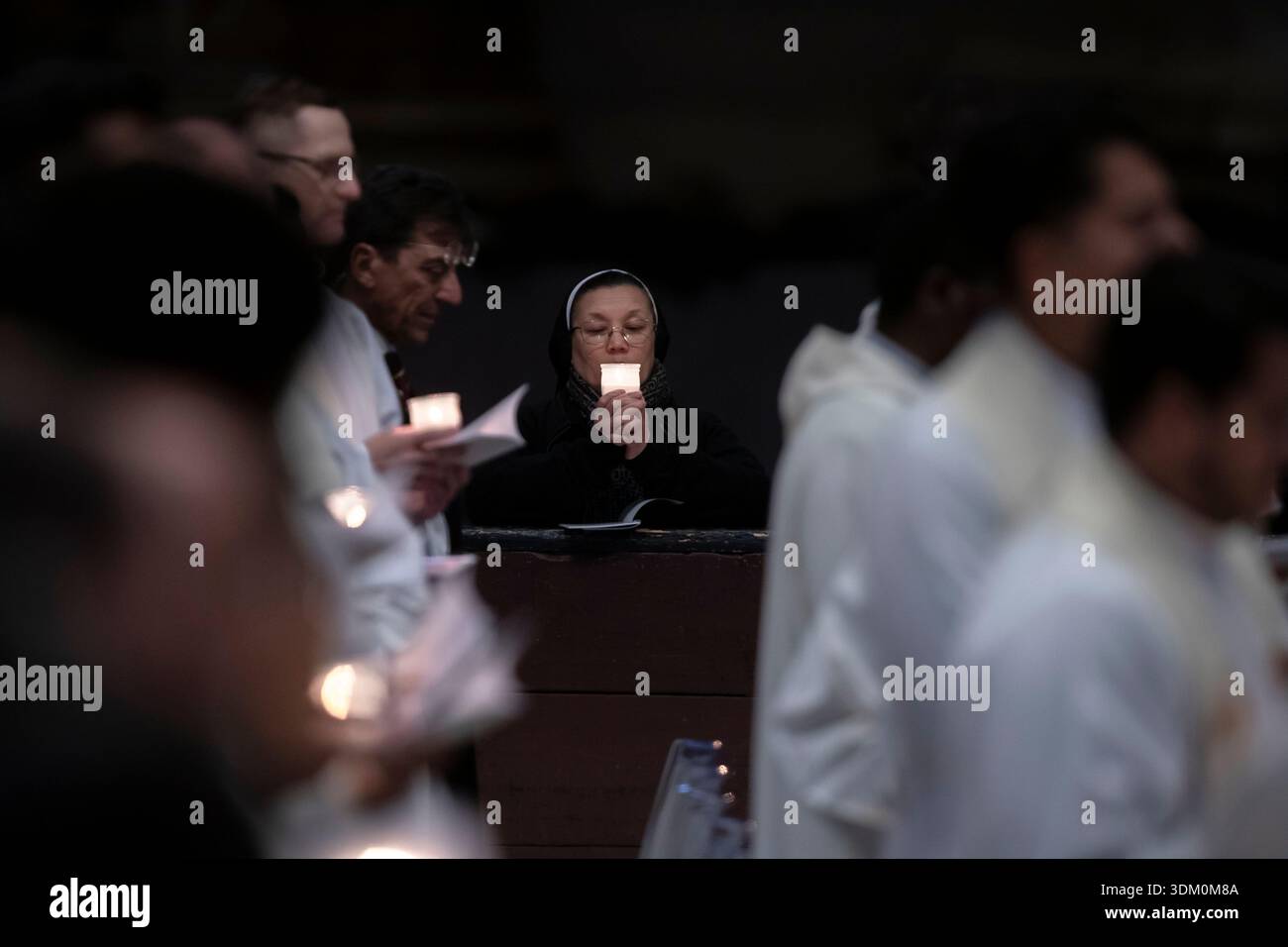A nun and priests hold candles at the beginning of a Mass on the Feast ...