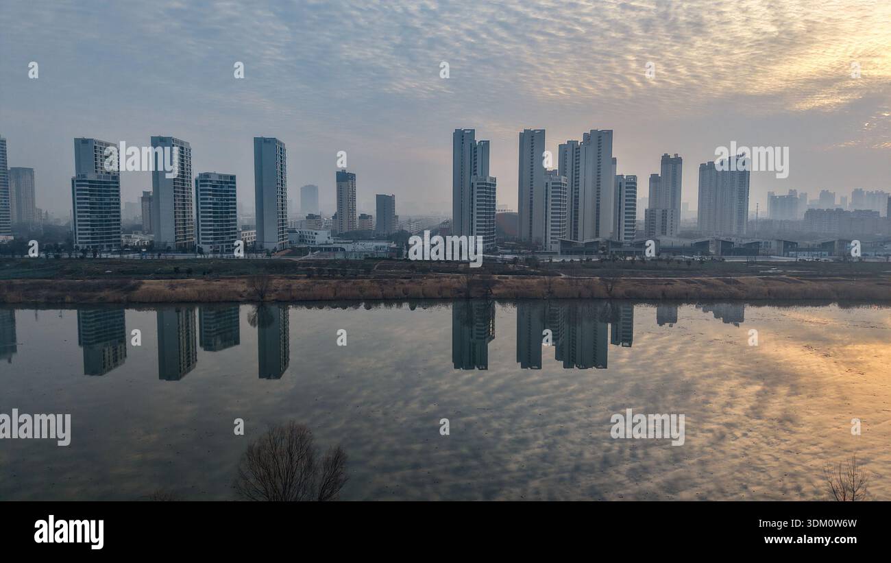 A serene early morning view of modern high-rise buildings reflected in ...