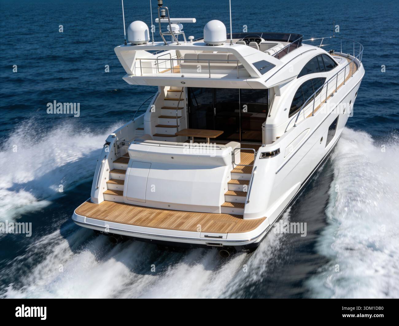 A large white boat is speeding through the water. The boat has a wooden ...