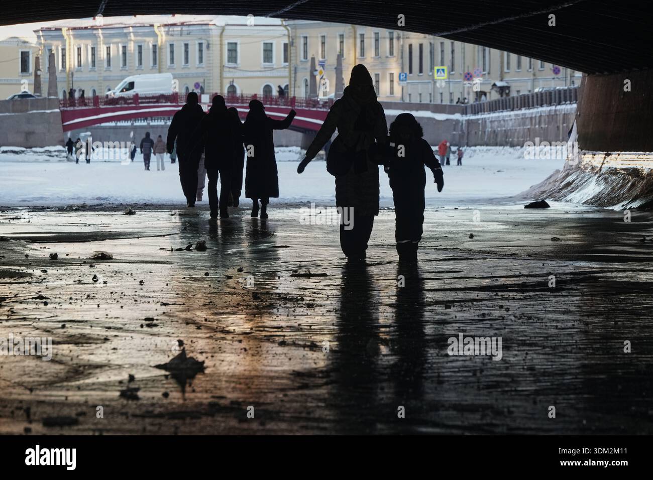 People walk under bridge on the ice of the frozen Moyka River in St ...