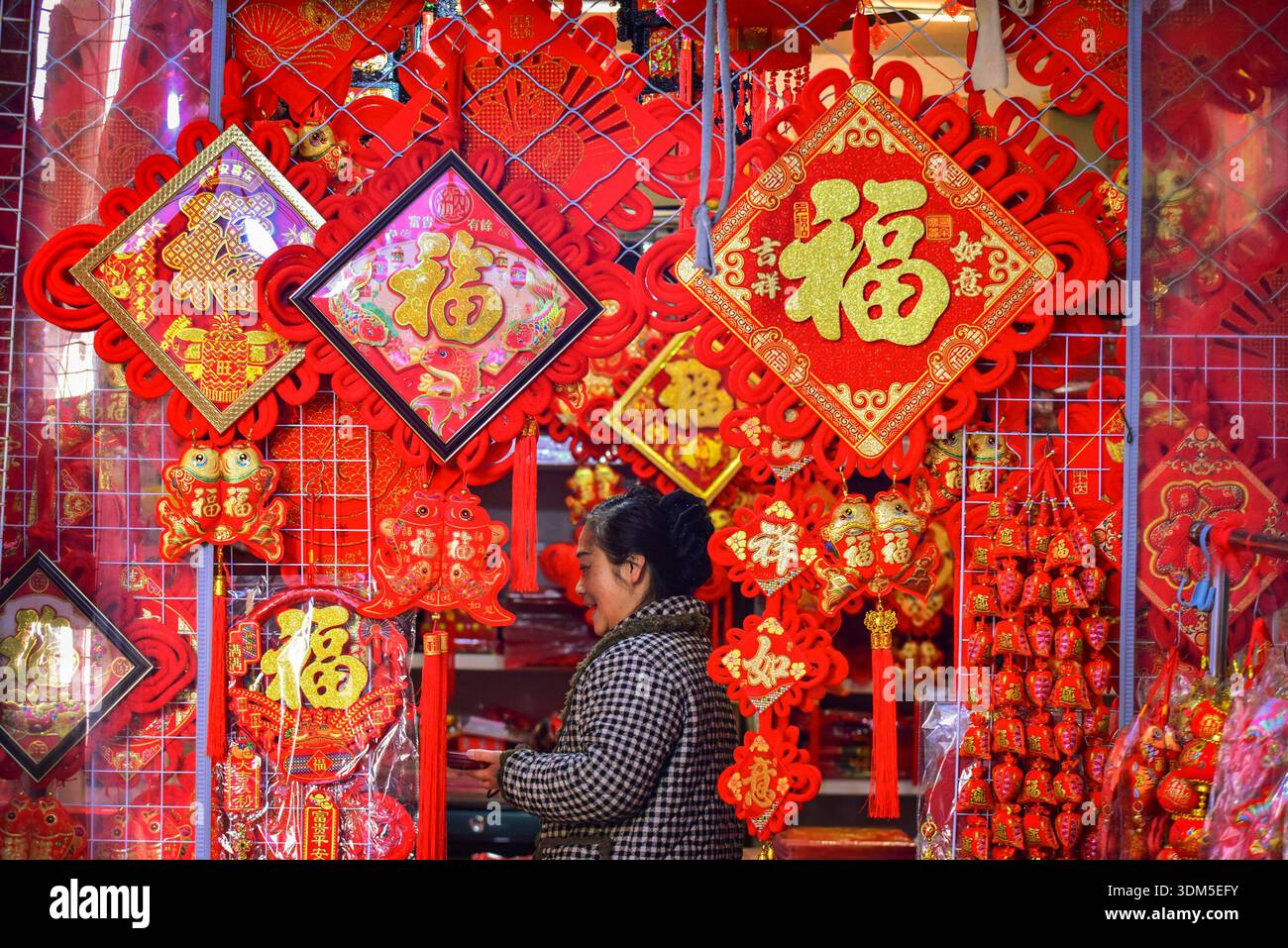 A woman browses a wide variety of red "Fu" character decorations ...