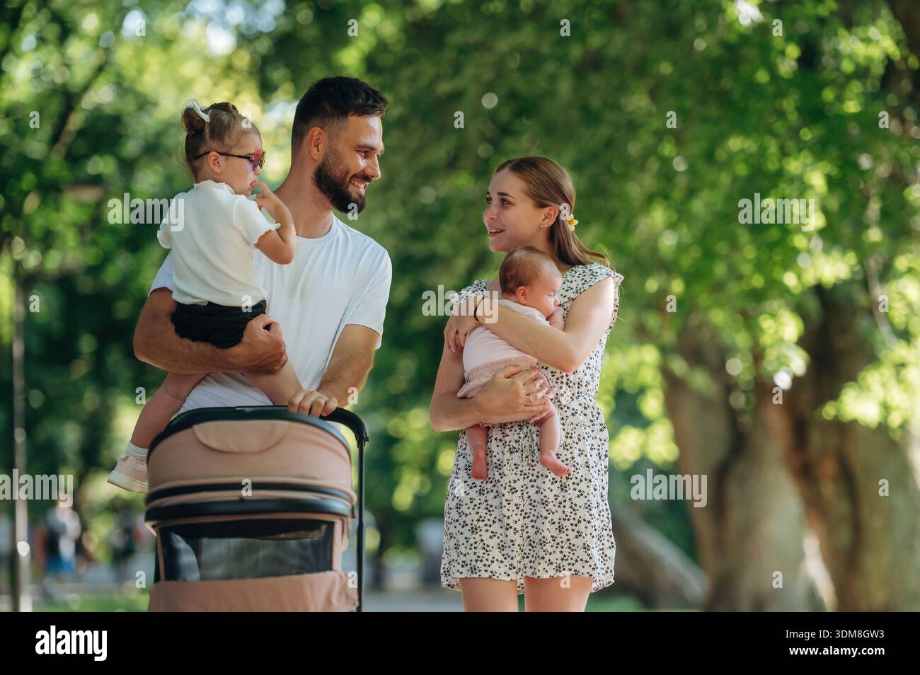 Couple is with daughter, newborn baby and cradle are having a walk ...