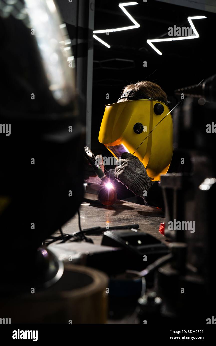 Worker welds metal with TIG process using tungsten electrode and argon ...