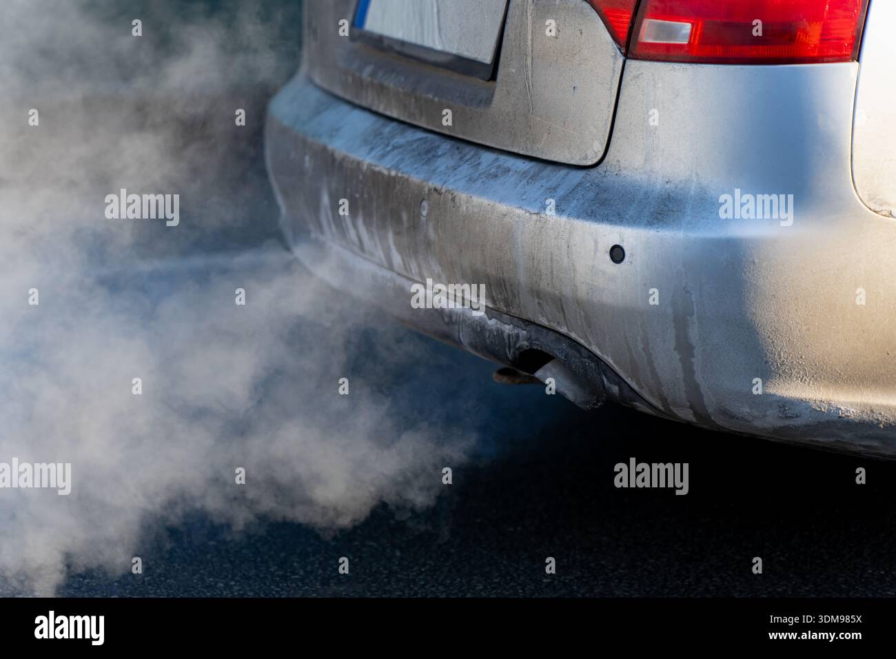Car exhaust fumes rising from tailpipe behind dirty bumper, closeup of ...