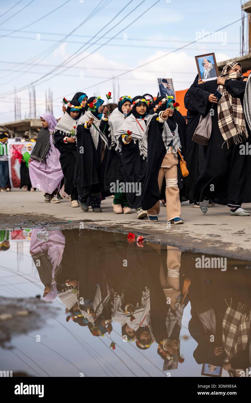 Shia Muslims are seen reflected in water as they walk during a rally ...