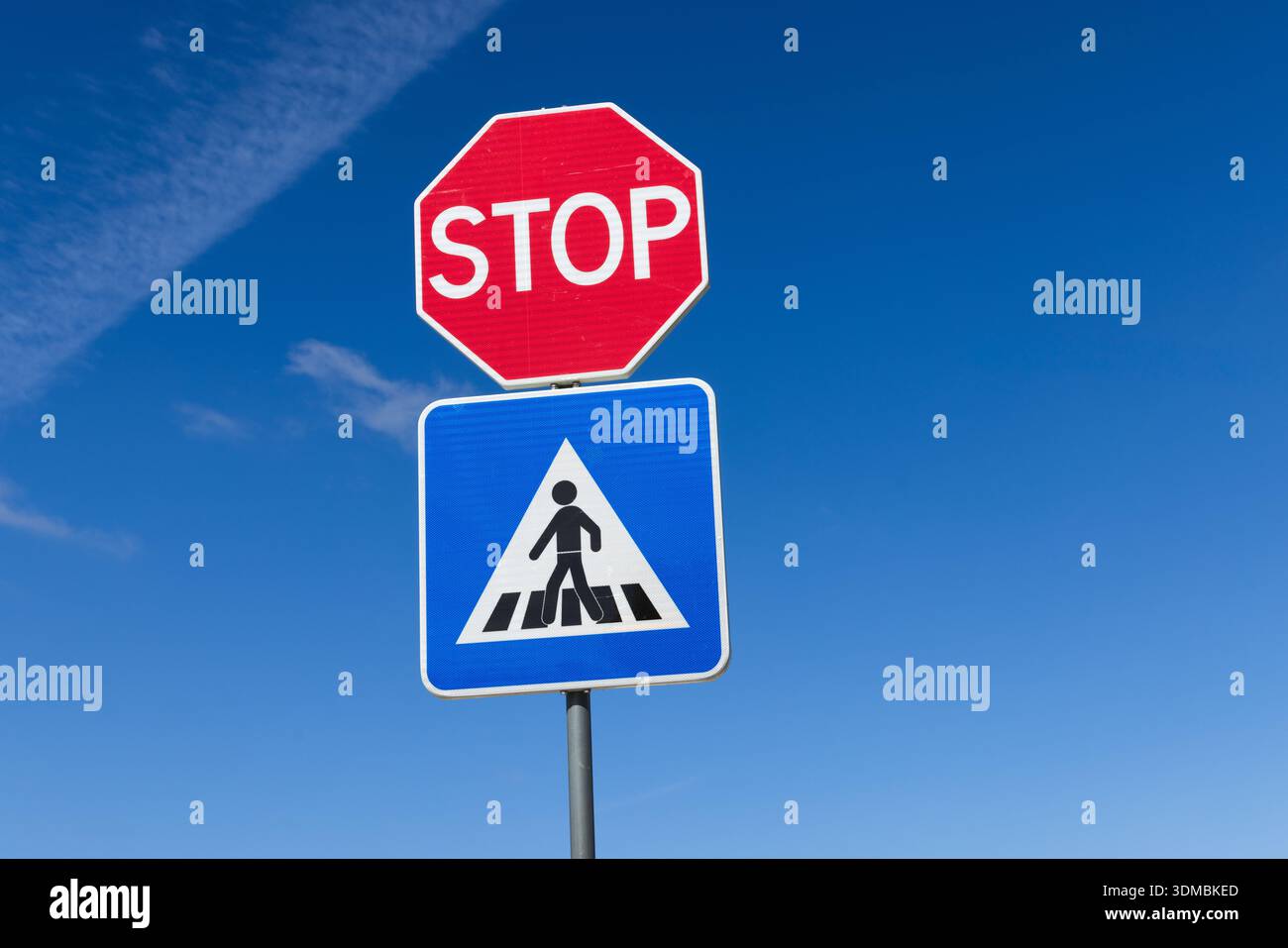 Red octagonal stop sign and blue pedestrian crossing road sign against ...