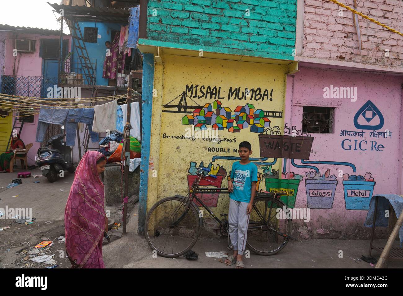 A boy stands beside a wall that shows a mural by the Rouble Nagi Art ...