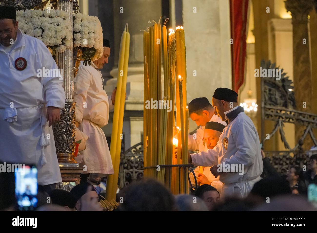 Catania Sicily, Italy - 5 February 2026. Workers passing candles to lit ...