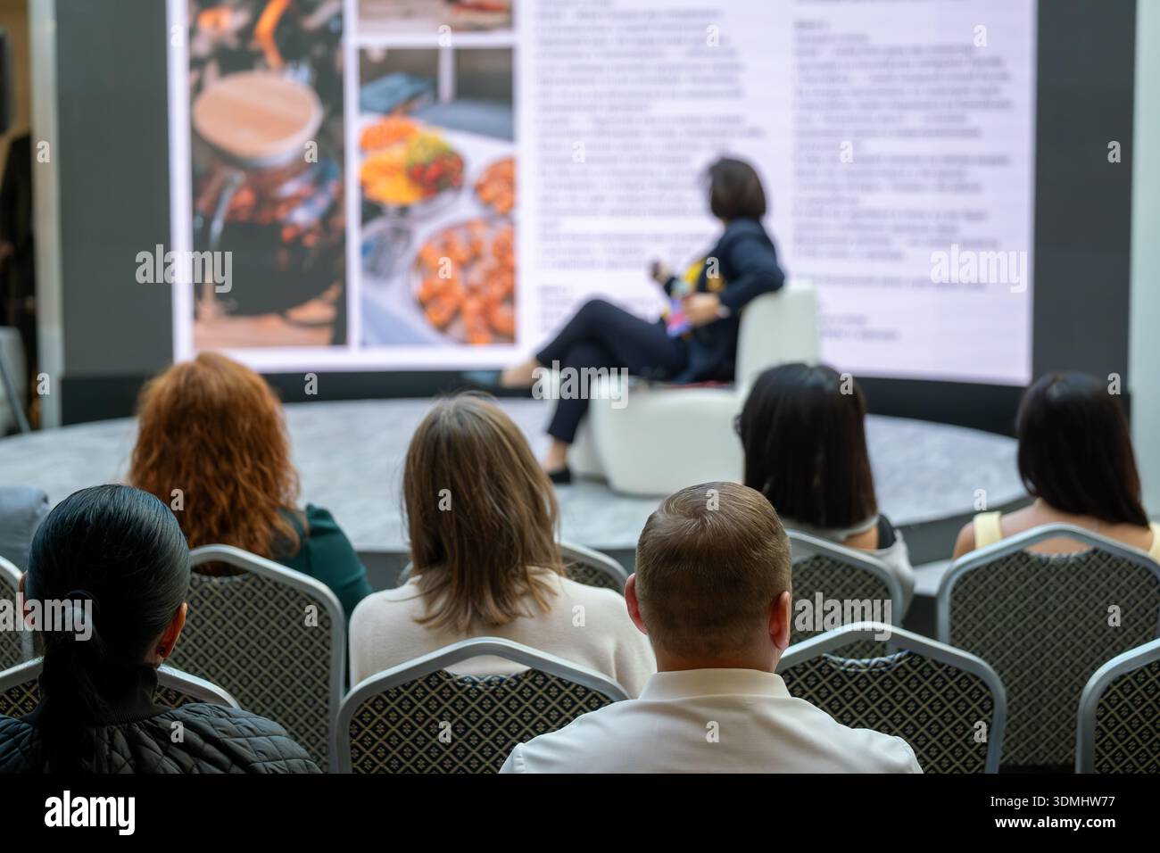 Audience sits facing stage during conference session watching speaker ...