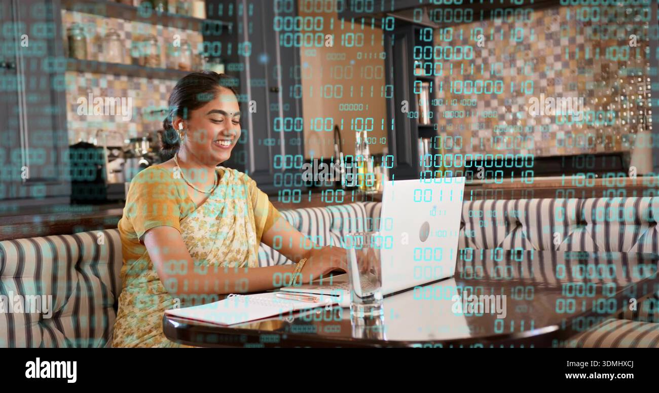 Typing Indian woman in yellow patterned sari at cafe booth, using white ...
