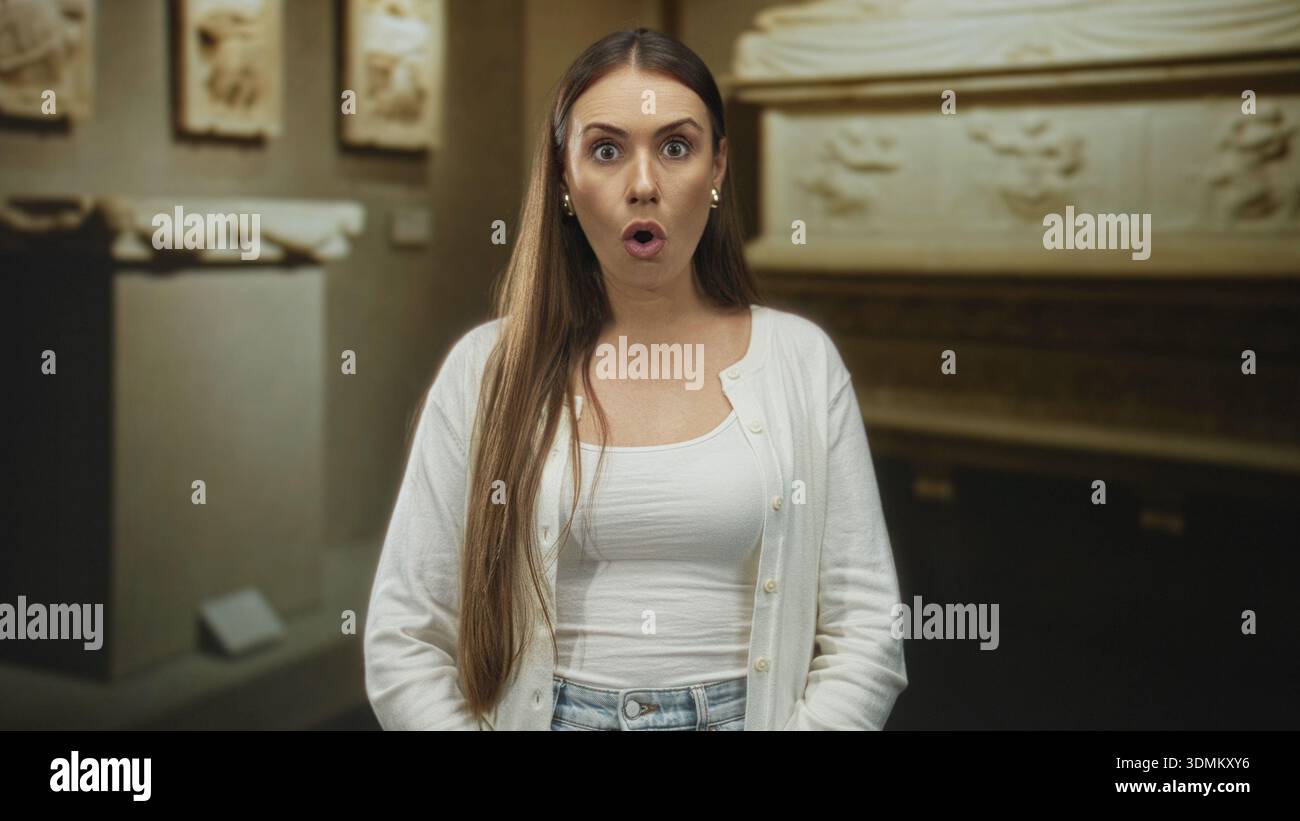 Young hispanic woman gasps with mouth open beside ancient stone ...
