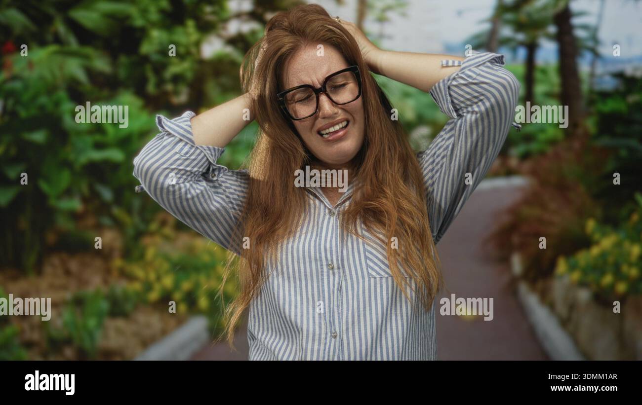 Woman with glasses covers ears and holds head amid lush green forest ...