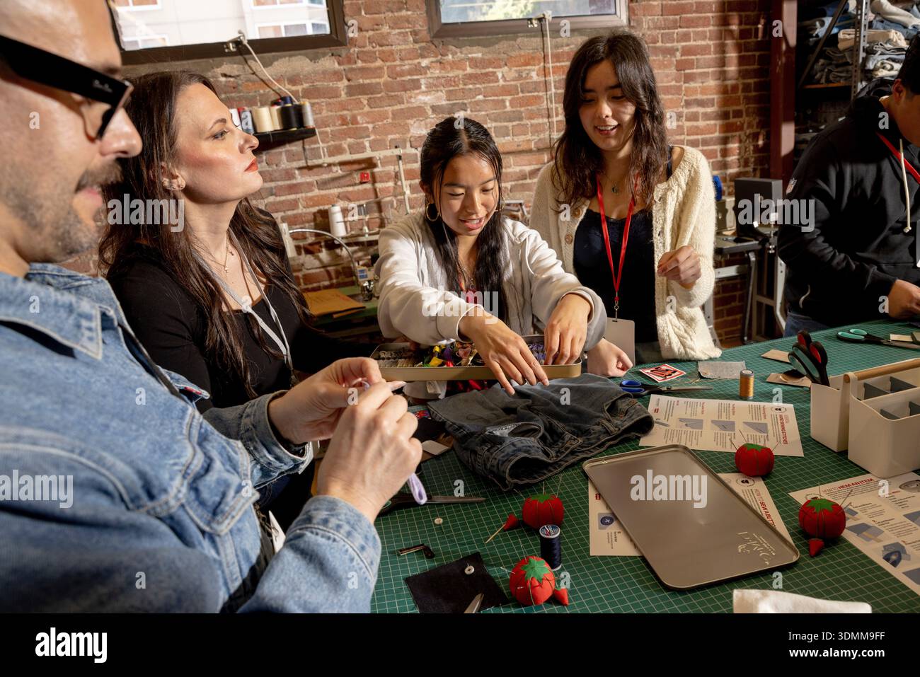 Attendees sew during a clothing repair and customization workshop for ...