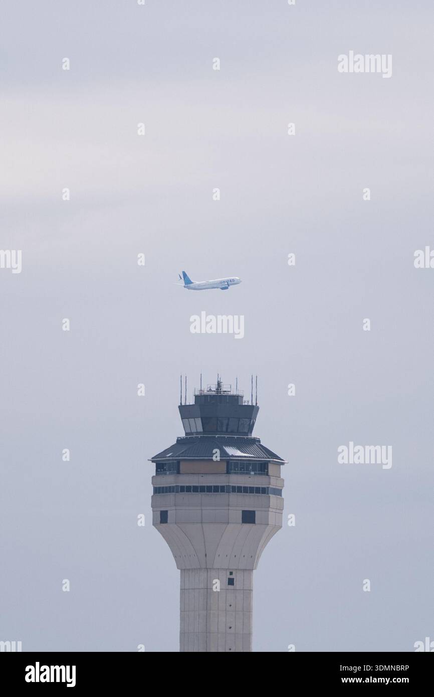 An airplane flies over an air traffic control tower at Dulles ...