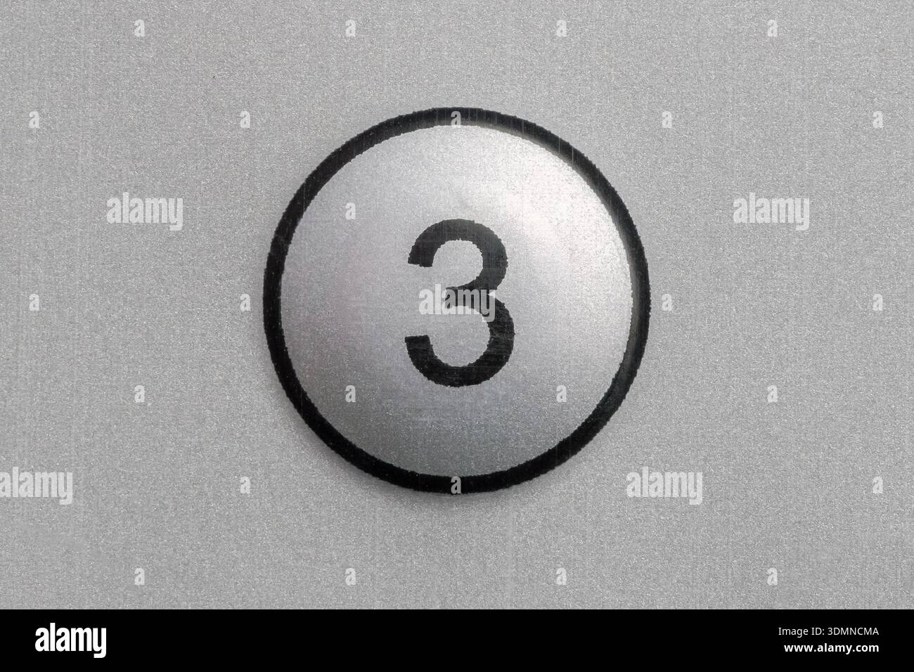 Round silver push button with number 3 on metallic panel, simple ...
