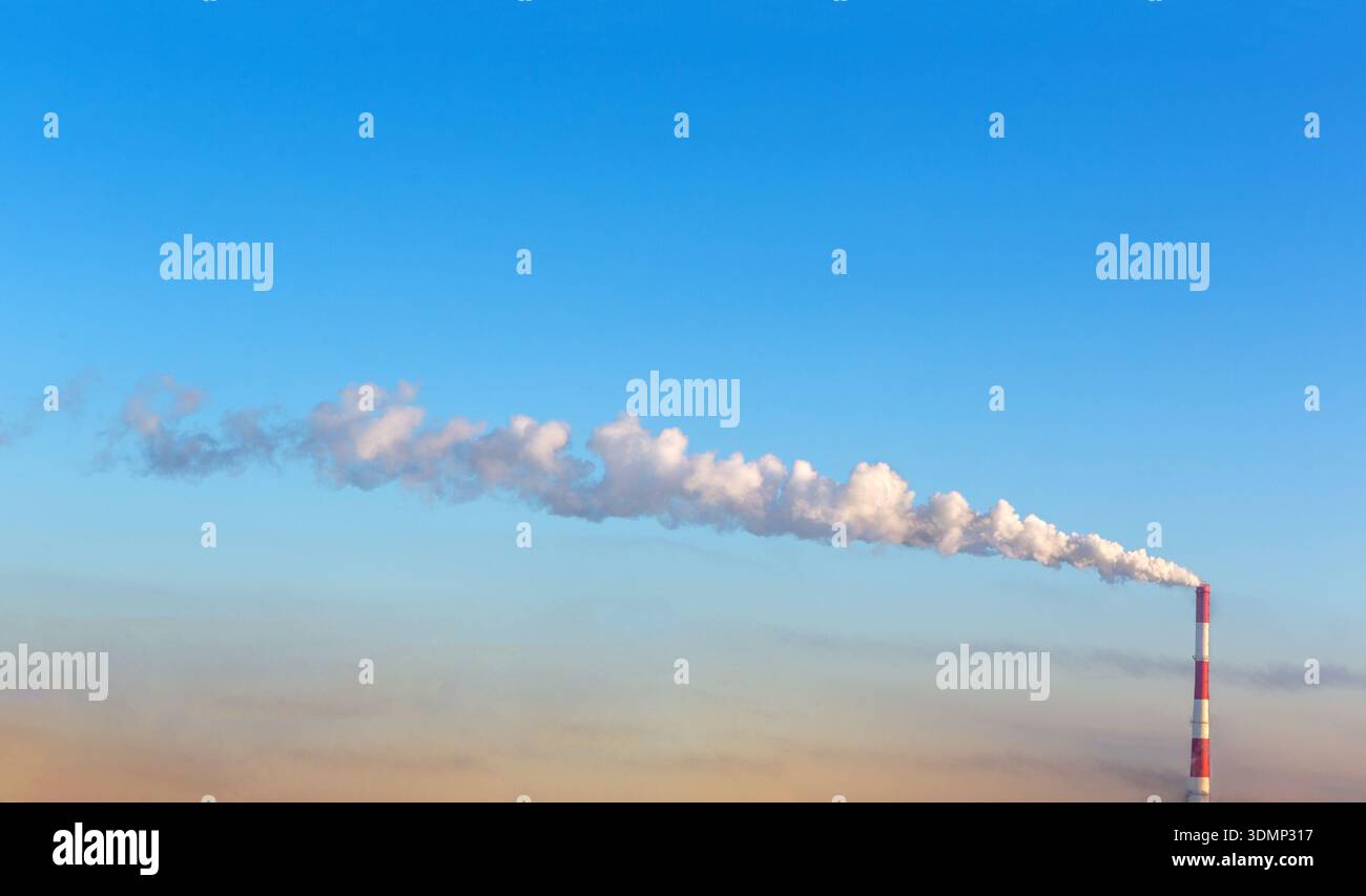 Smoking smoke stack. Smokestack with smoke against a blue sky and low ...
