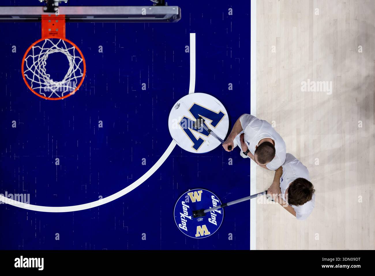 Floor sweepers stand on the court during an NCAA college basketball ...