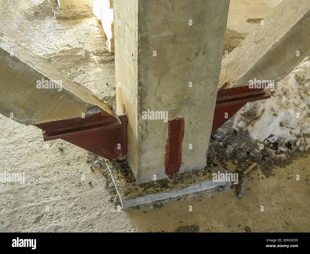 A close-up view shows the base of a concrete support pillar with metal ...