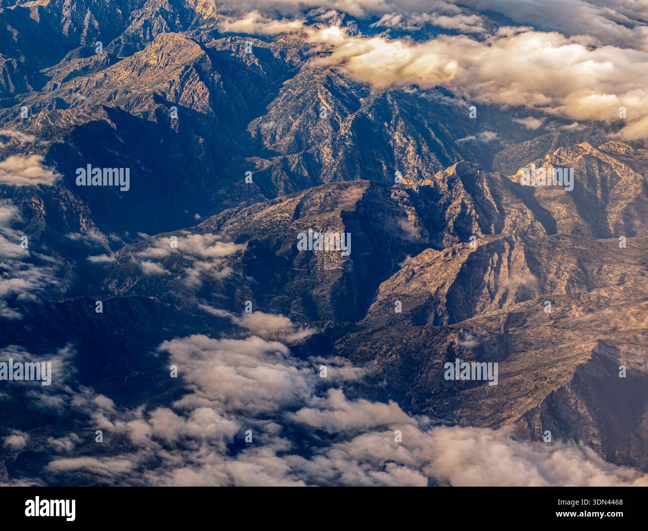 Bird's-eye view of towering peaks and deep ravines, with soft clouds ...