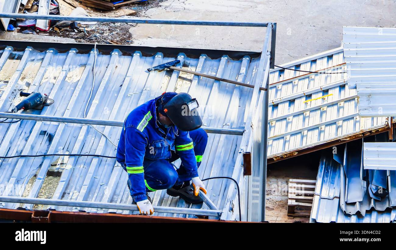 A construction worker wearing a blue uniform, A construction worker ...