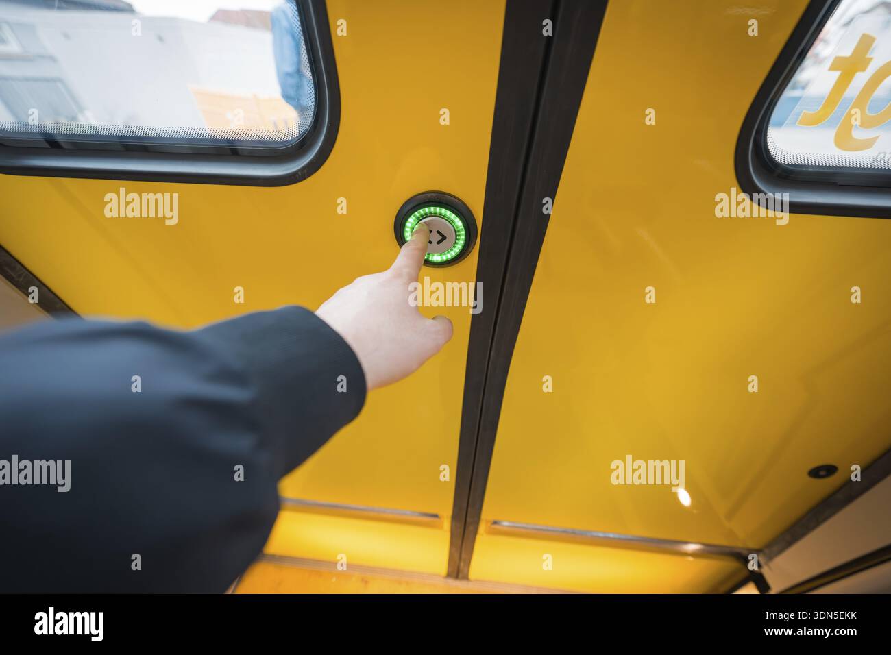 Hand presses button on yellow train door, surrounded by windows ...