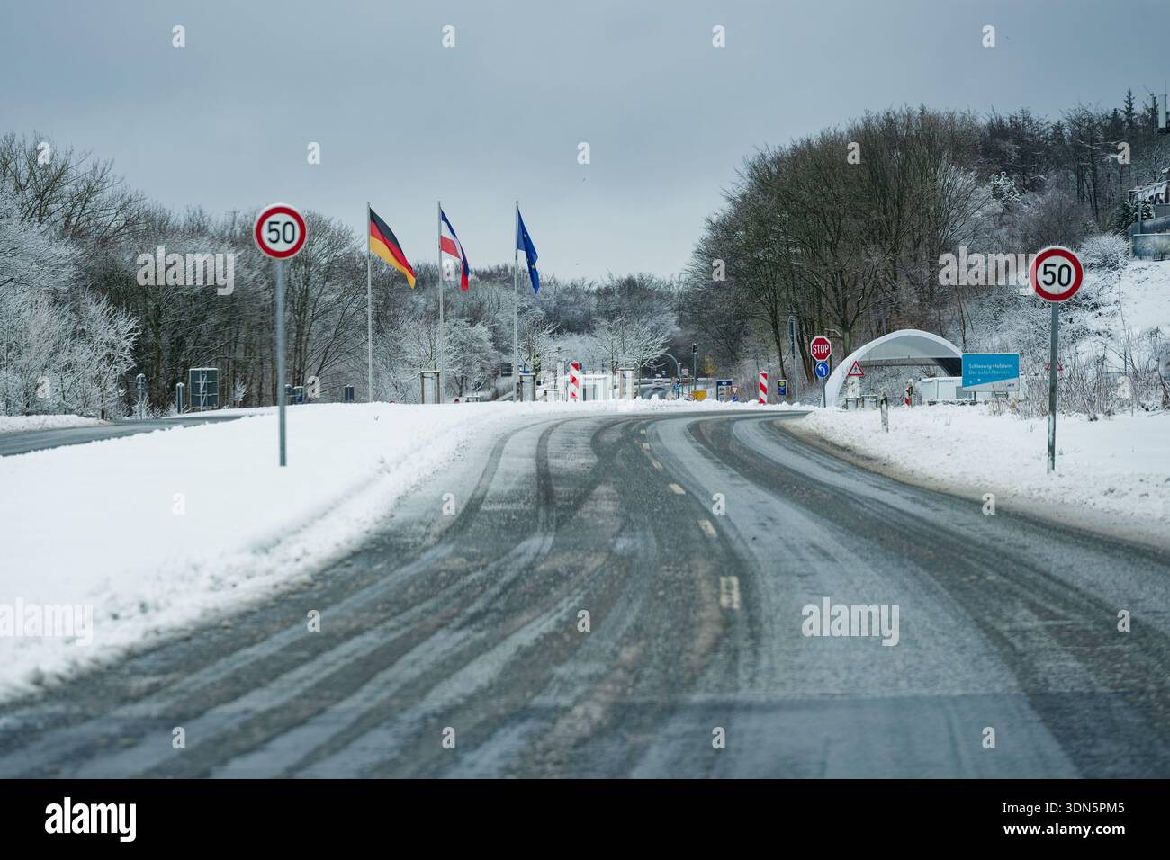 Snow covered border road with visible national flags and speed limit ...