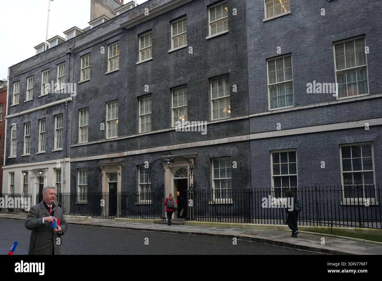 A television reporter watches as members of staff arrive for outside 10 ...