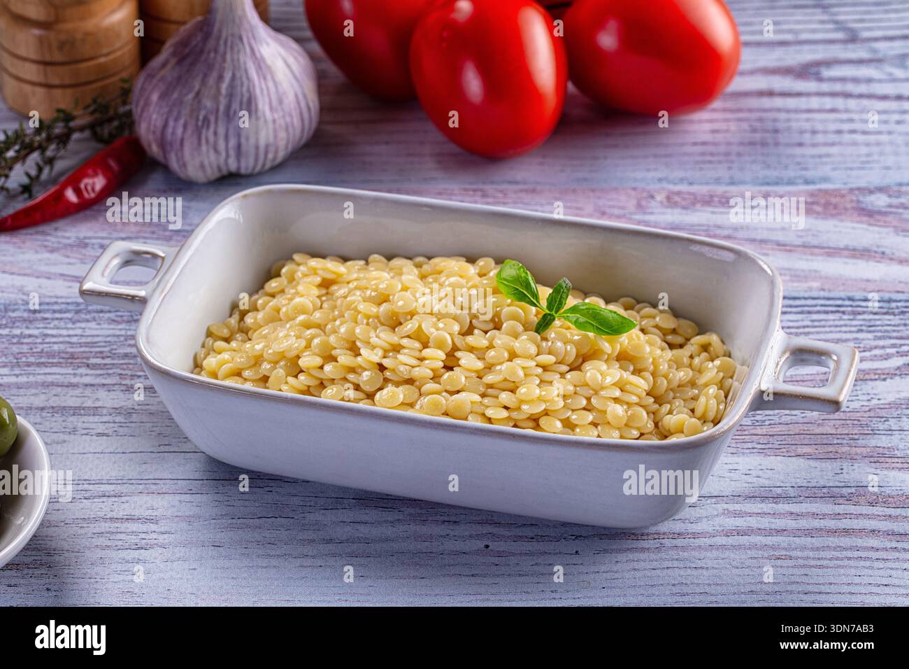 Boiled ptitim pasta served basil and olives Stock Photo - Alamy