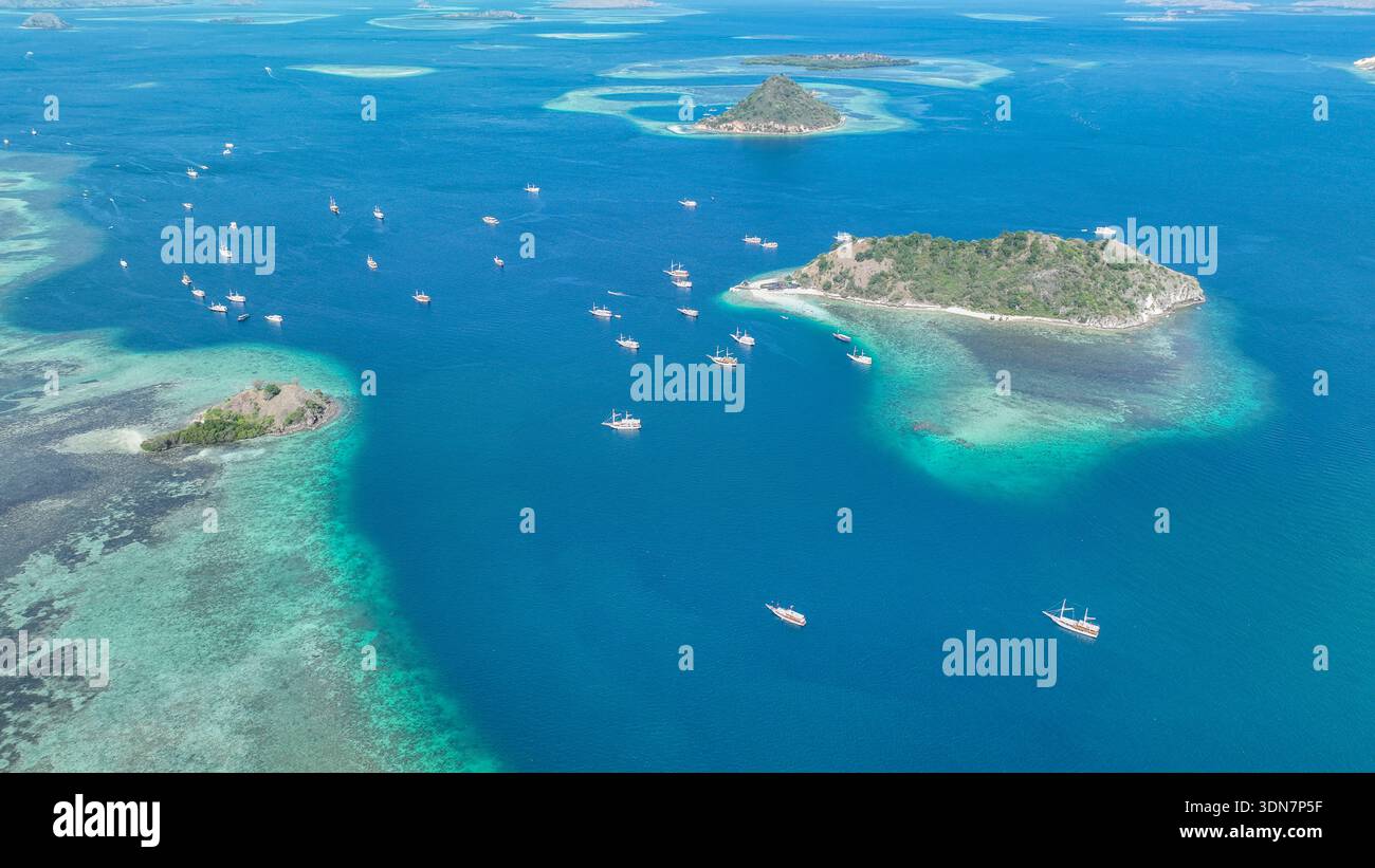 Boats drift between Kelor Island and nearby reefs, tracing white wakes ...